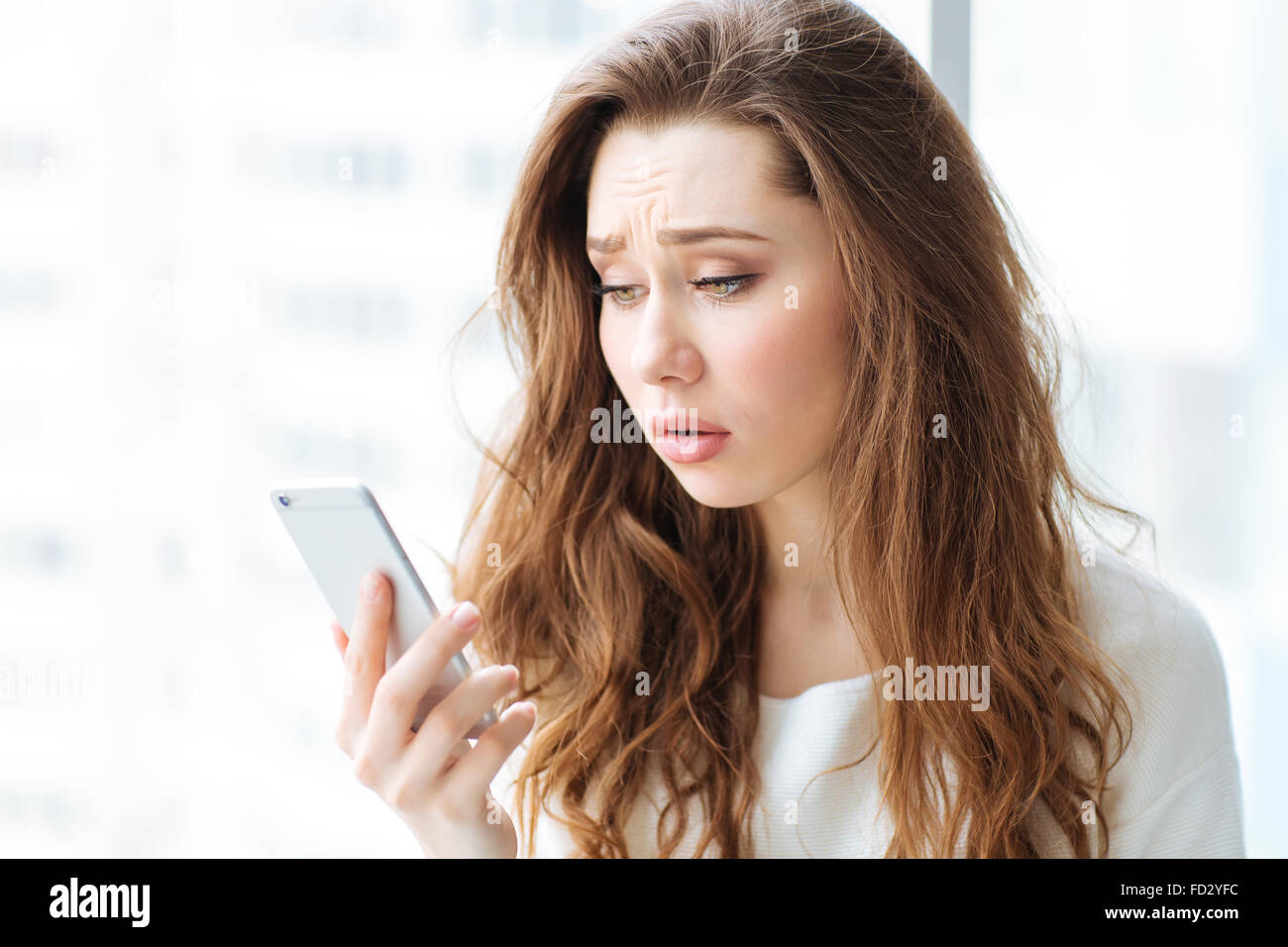 Portrait of a sad woman holding smartphone Stock Photo - Alamy