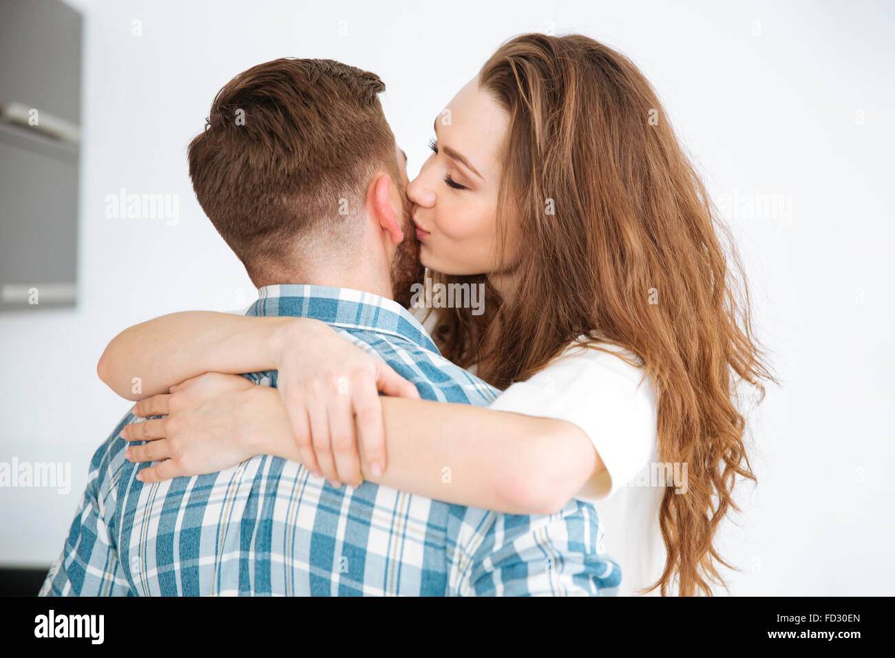 Portrait of a young woman hugging and kissing her boyfriend at home Stock Photo - Alamy