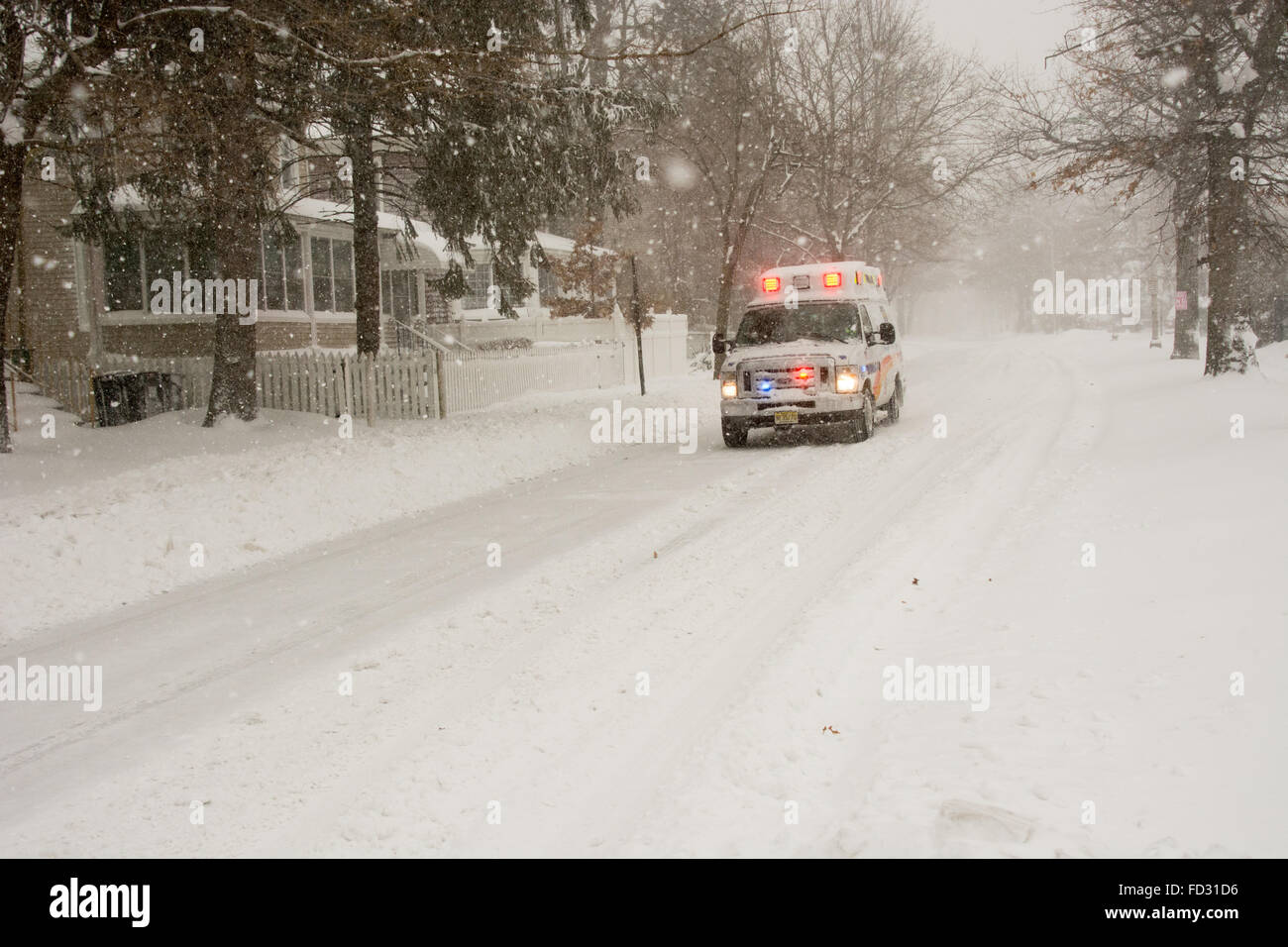 An EMS vehicle travels through the snow on a semi-plowed street Stock ...