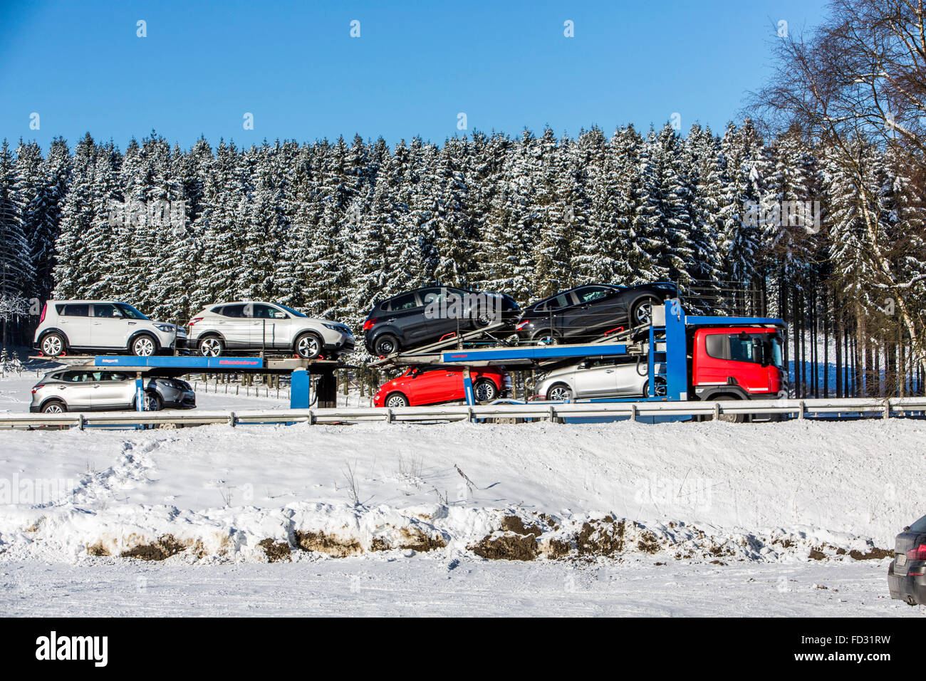 Truck and trailer with cars, country road, snowy landscape, Sauerland ...