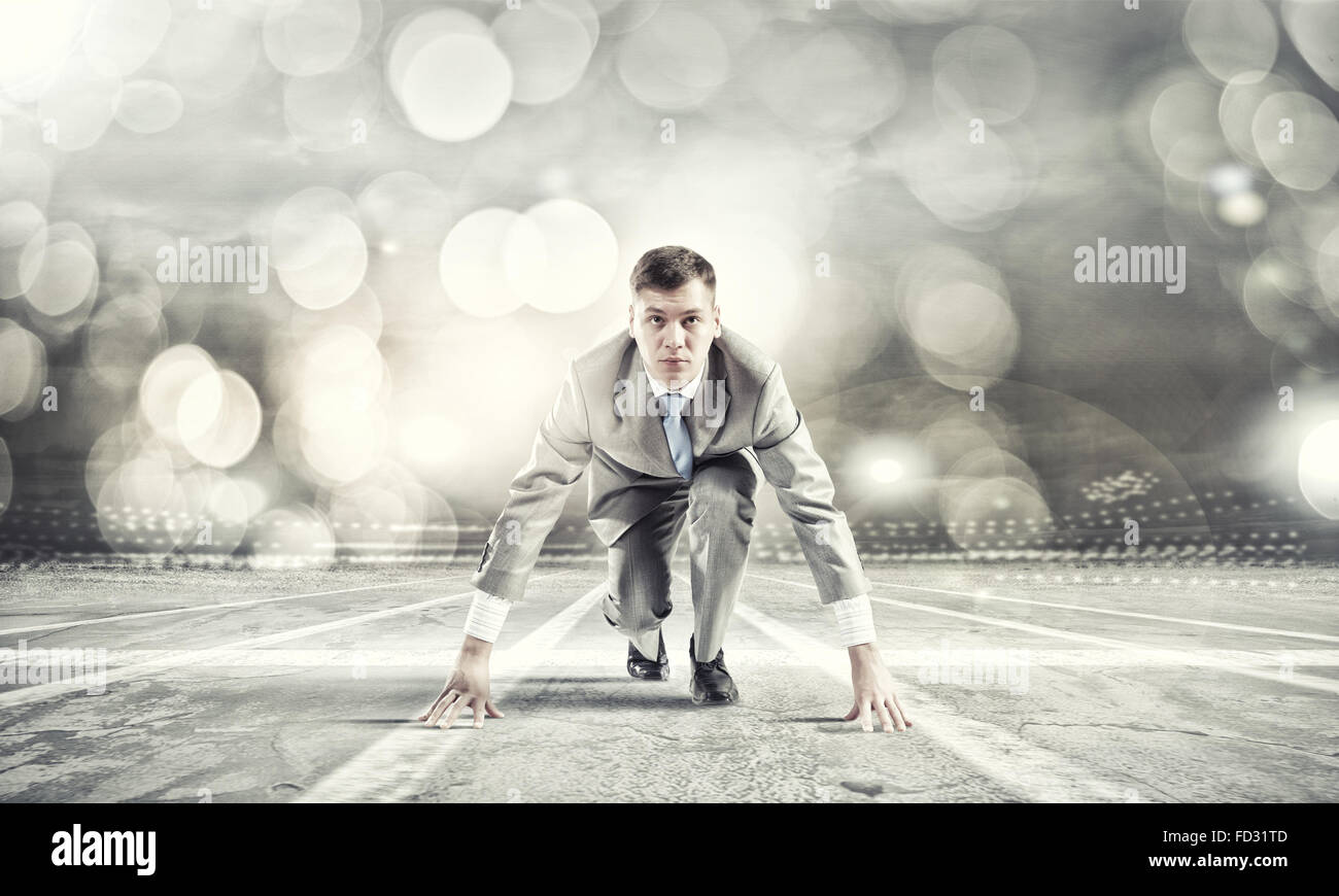 Young businessman standing in start pose ready to run Stock Photo - Alamy