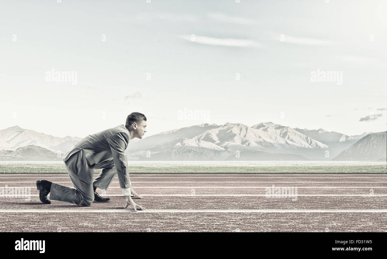 Young businessman standing in start pose ready to run Stock Photo - Alamy