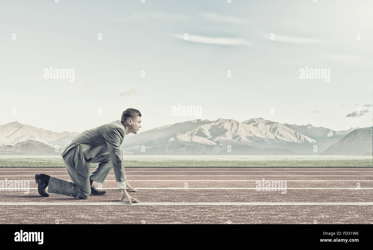 Young businessman standing in start pose ready to run Stock Photo - Alamy