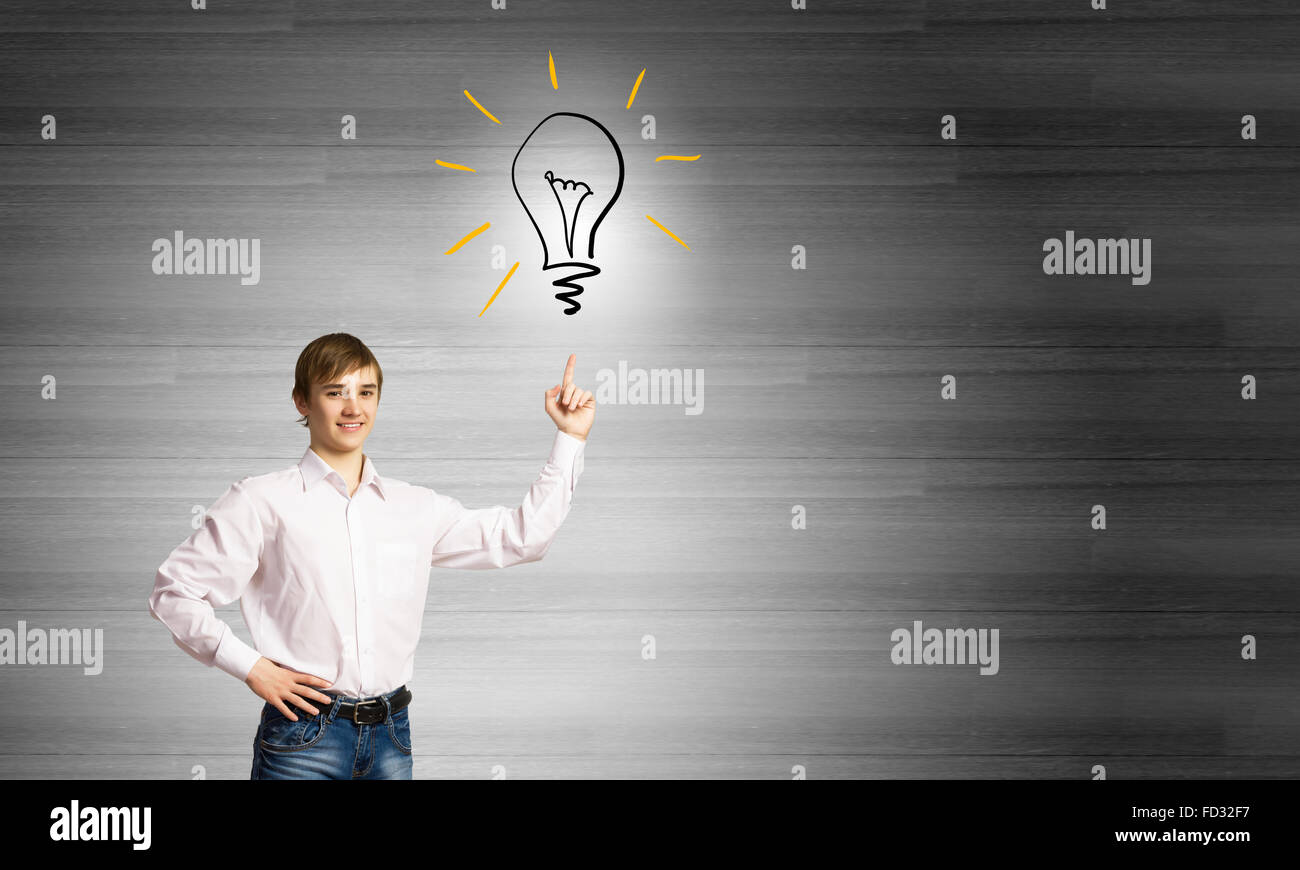 Smiling school boy pointing at light bulb with finger Stock Photo - Alamy