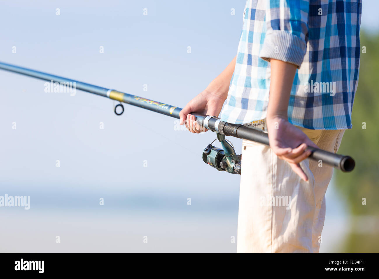Close-up of hands of a boy with a fishing rod that is fishing on the ...