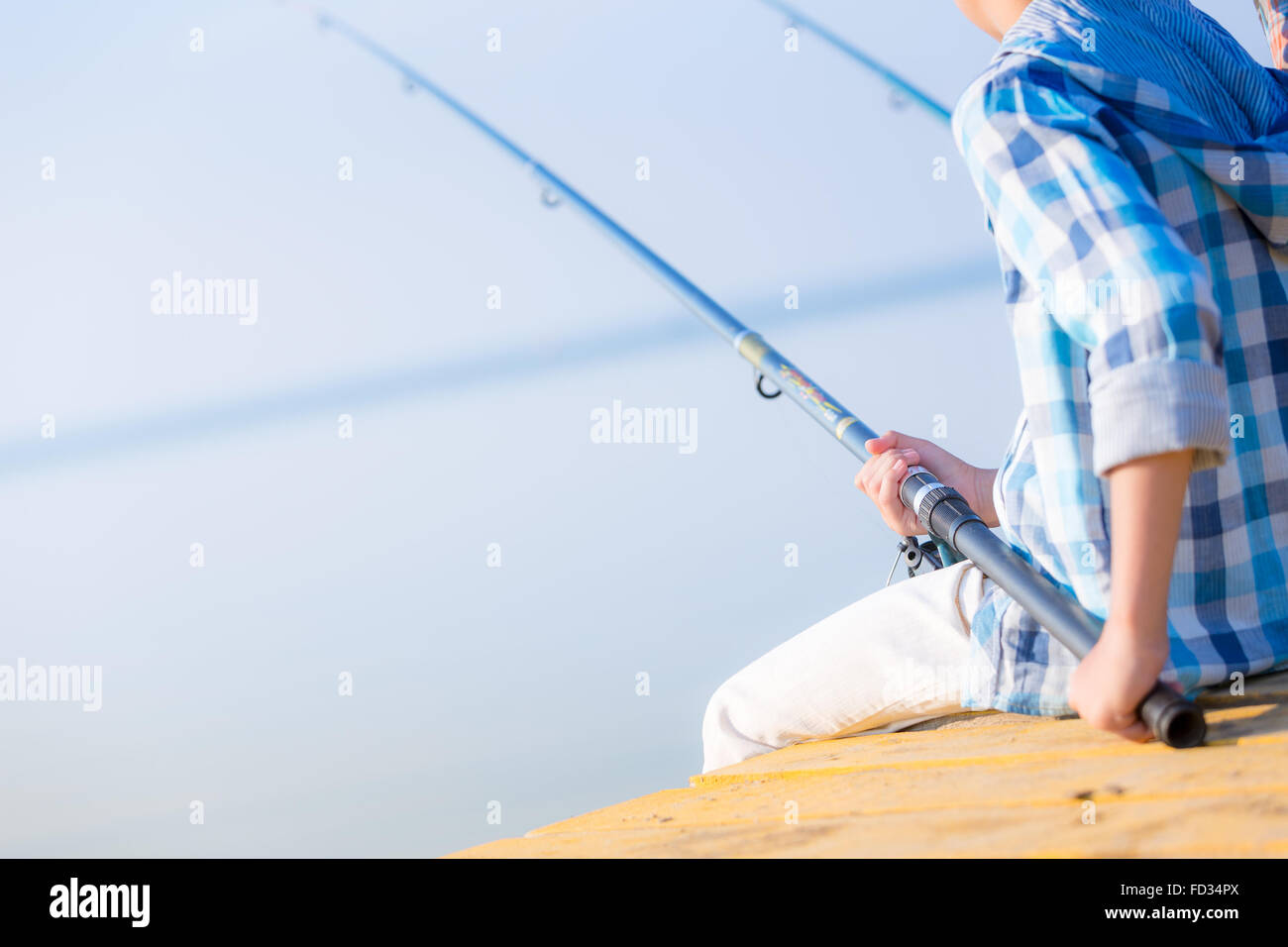 Close-up of hands of a boy with a fishing rod that is fishing on the ...