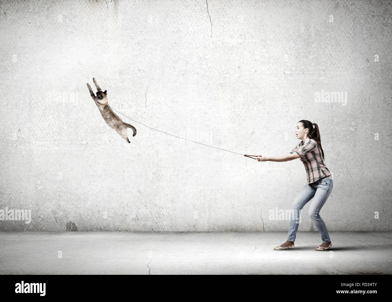 Young woman in casual catching cat with rope Stock Photo - Alamy