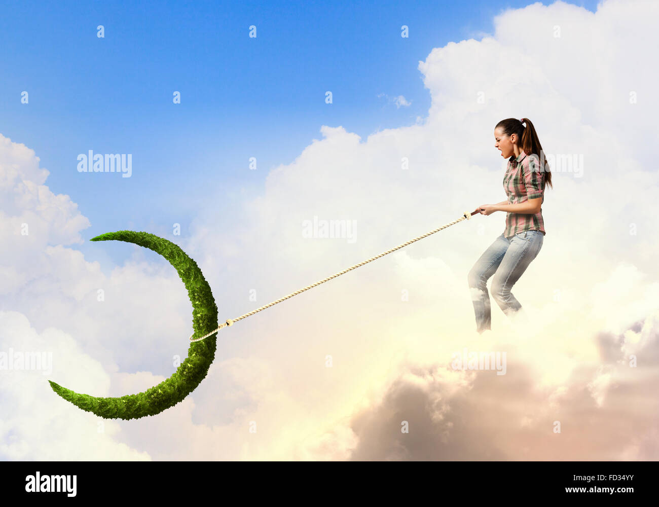 Young woman in casual catching moon with rope Stock Photo - Alamy