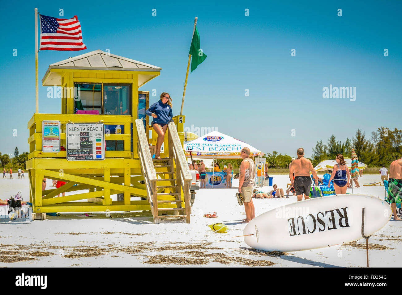 A female lifeguard descends stairs of bright yellow lifeguard station ...