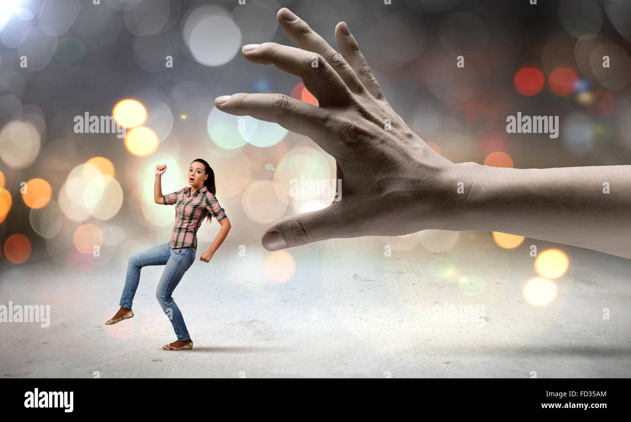 Young woman in casual running away from big hand Stock Photo - Alamy