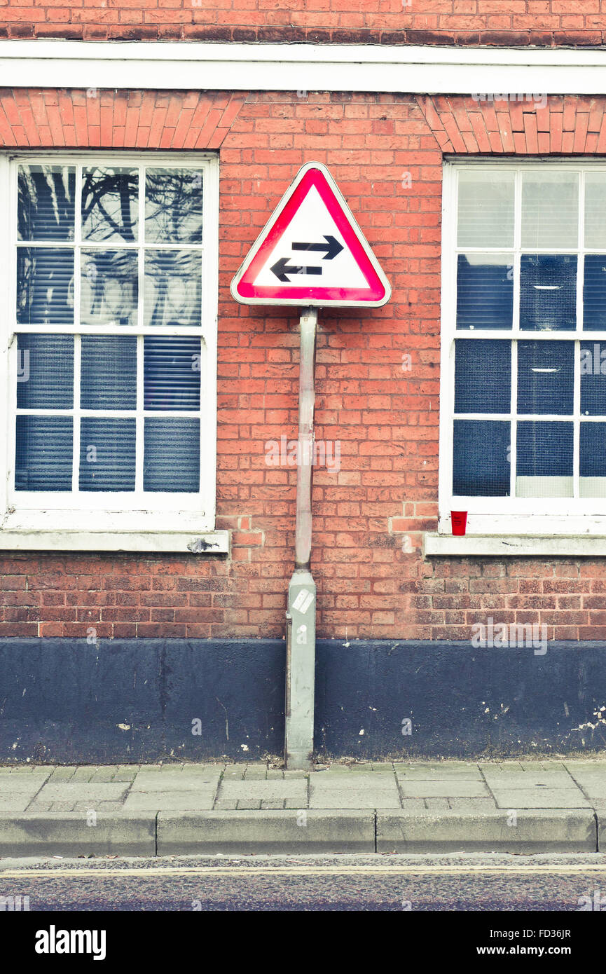 A warning sign for a 2 way street against a red brick wall building ...