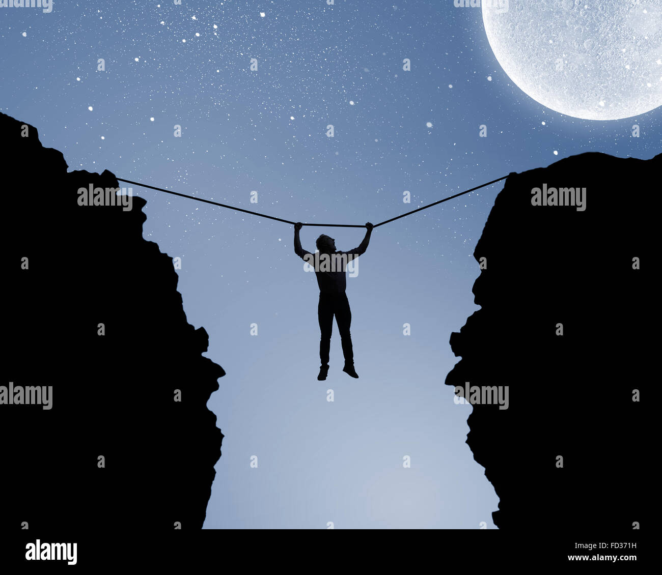 Silhouette of man hanging on rope above gap Stock Photo - Alamy