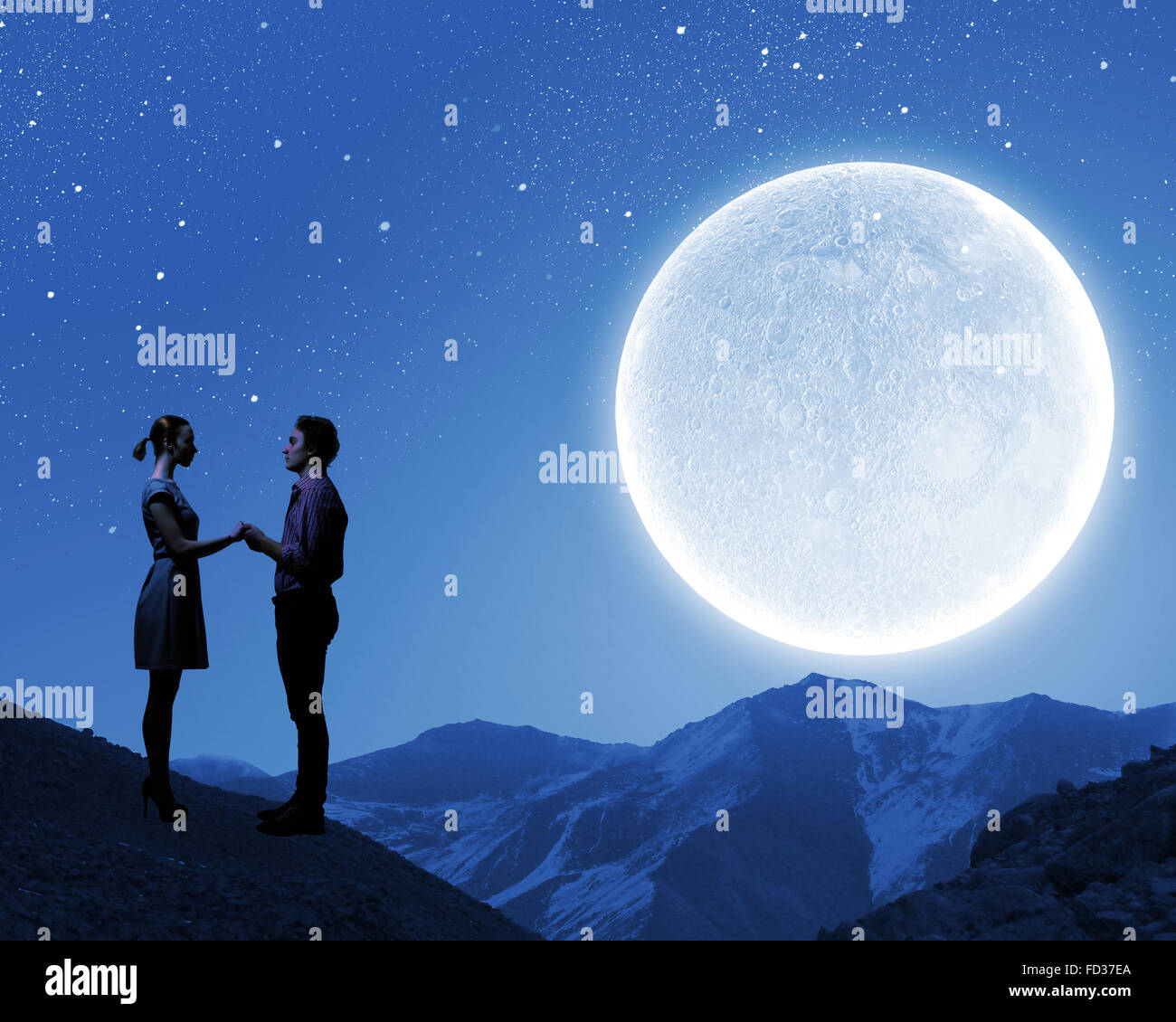 Silhouettes of young romantic couple standing under the moon light ...