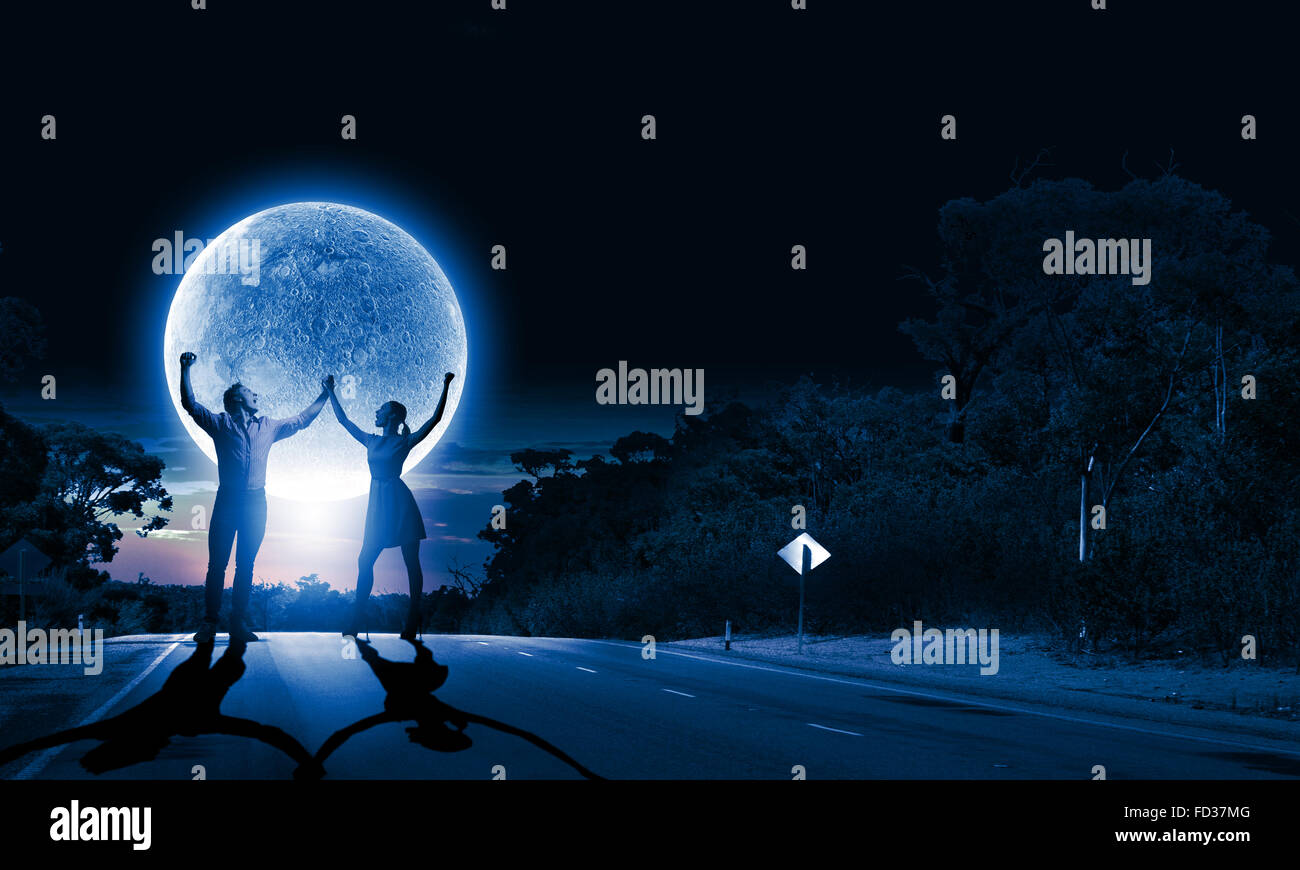 Silhouettes of young romantic couple standing under the moon light ...