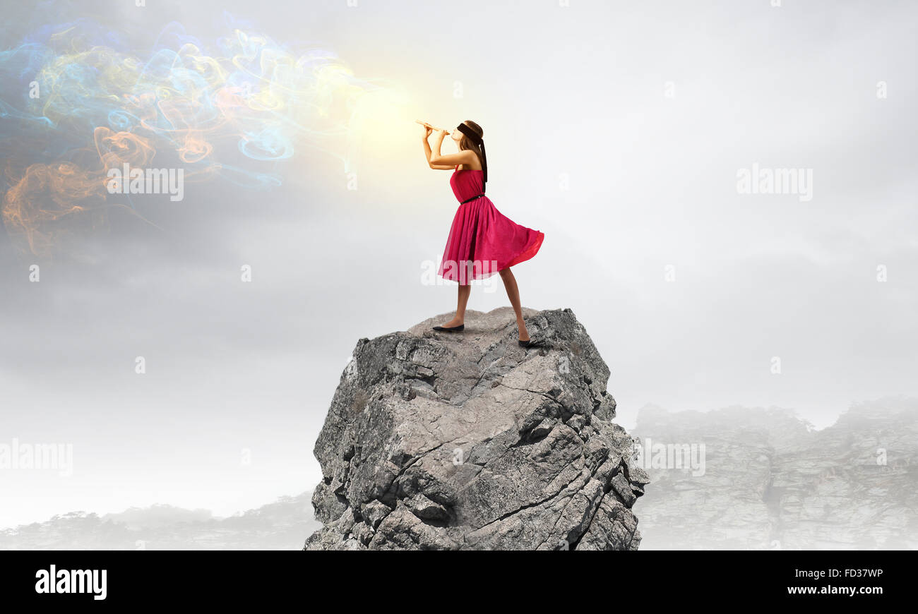 Young woman in red dress on rock playing fife Stock Photo - Alamy