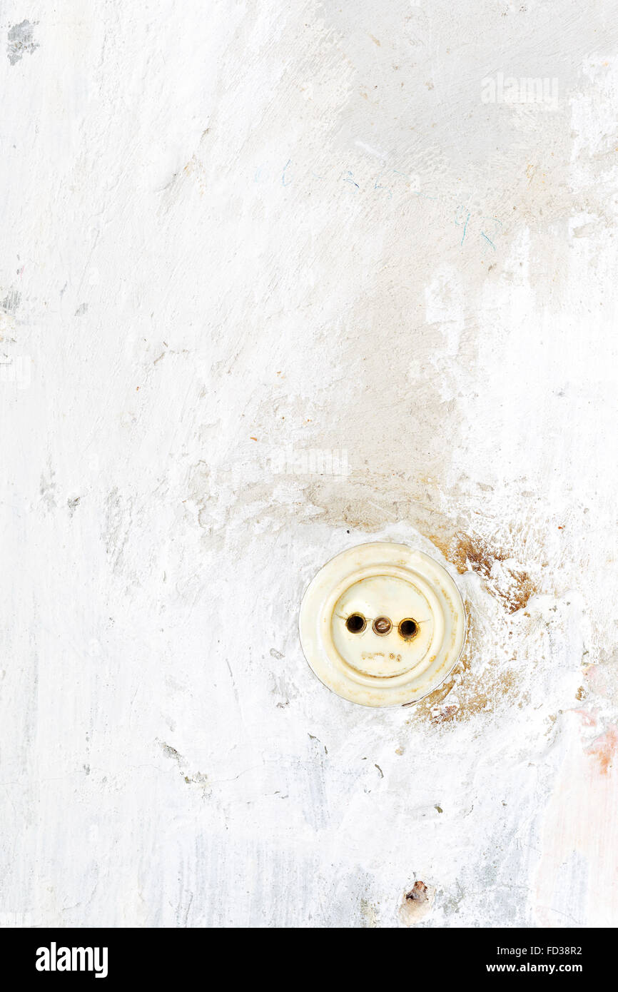 Vintage outlet in the old plastered wall with cracks and scratches ...