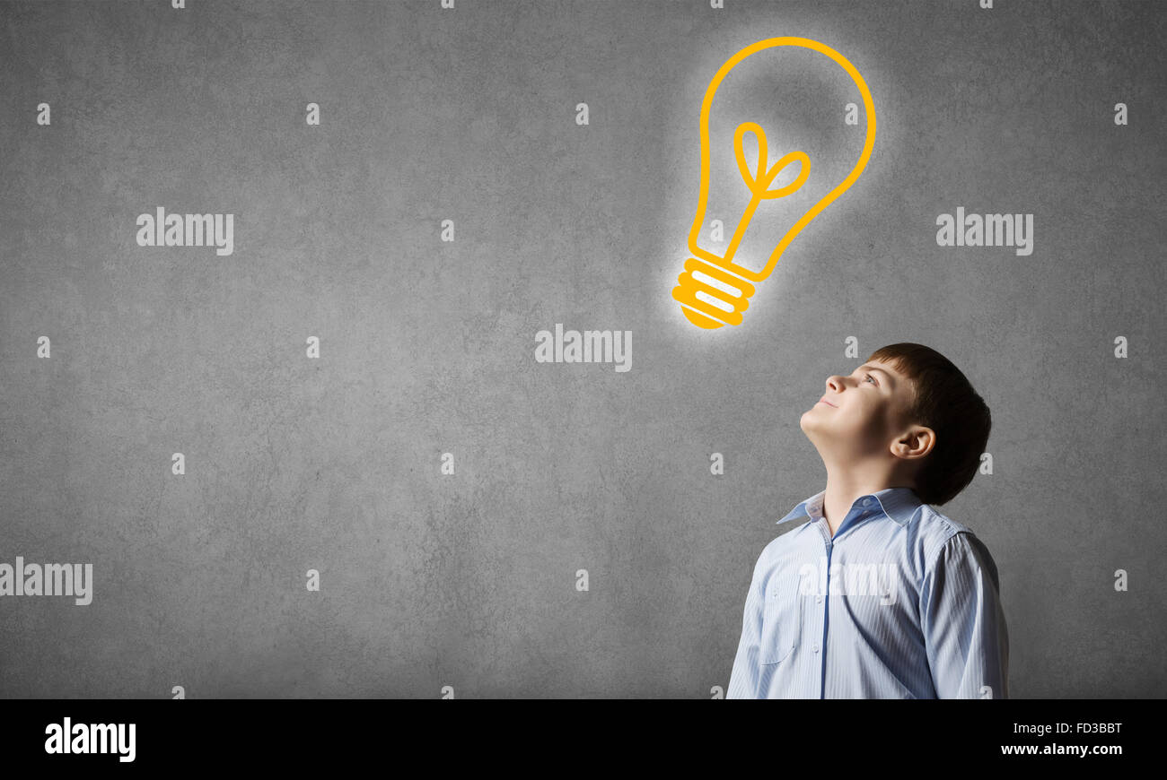Young boy of school age looking up at light bulb Stock Photo - Alamy