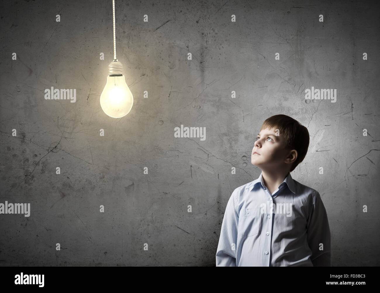 Young boy of school age looking up at light bulb Stock Photo - Alamy