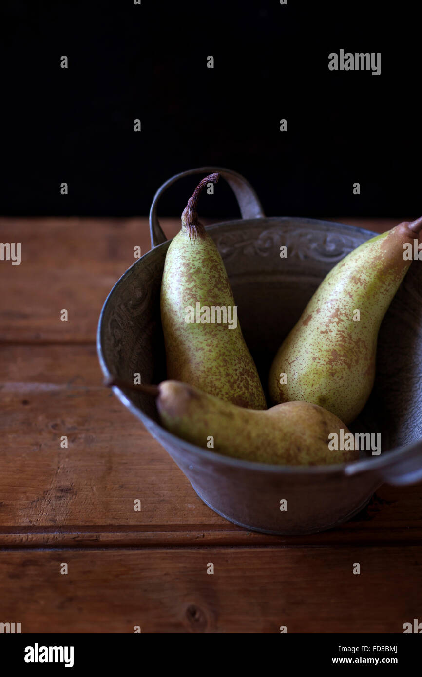 Three pears in metal bucket on a wooden background Stock Photo - Alamy