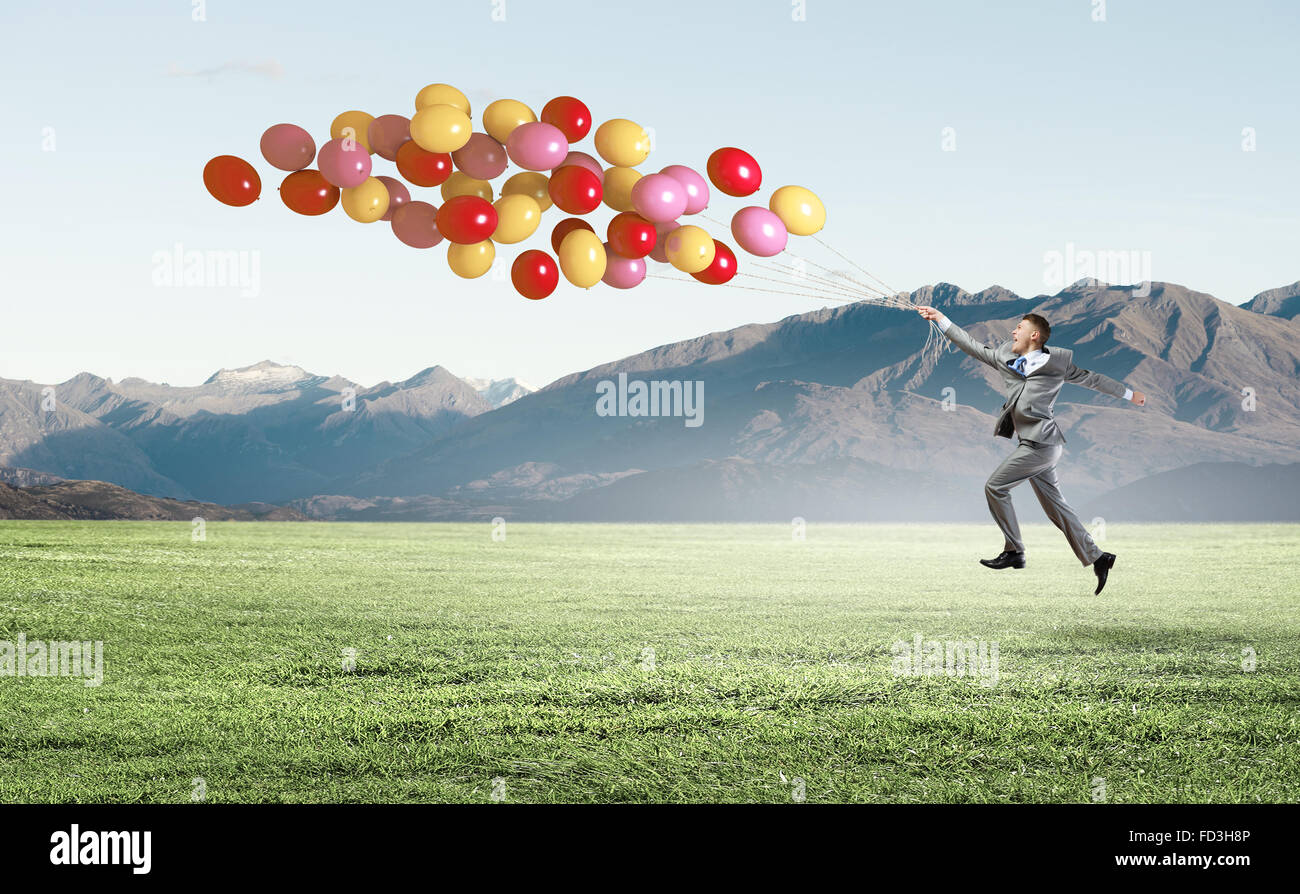 Cheerful businessman running with bunch of colorful balloons Stock ...
