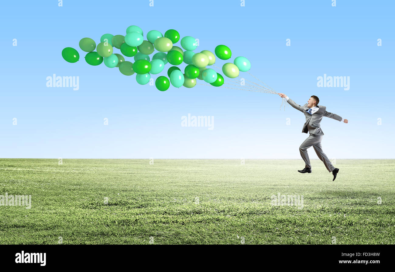 Cheerful businessman running with bunch of colorful balloons Stock ...