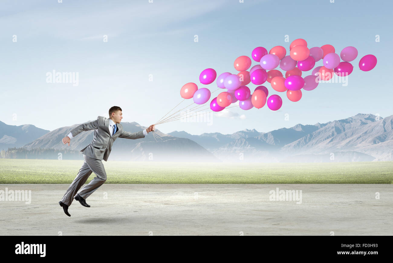 Cheerful businessman running with bunch of colorful balloons Stock ...