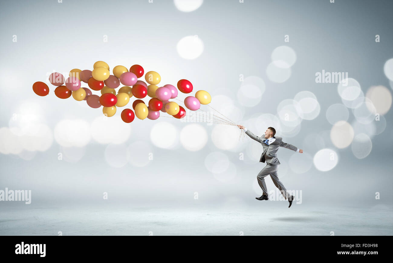 Cheerful businessman running with bunch of colorful balloons Stock ...