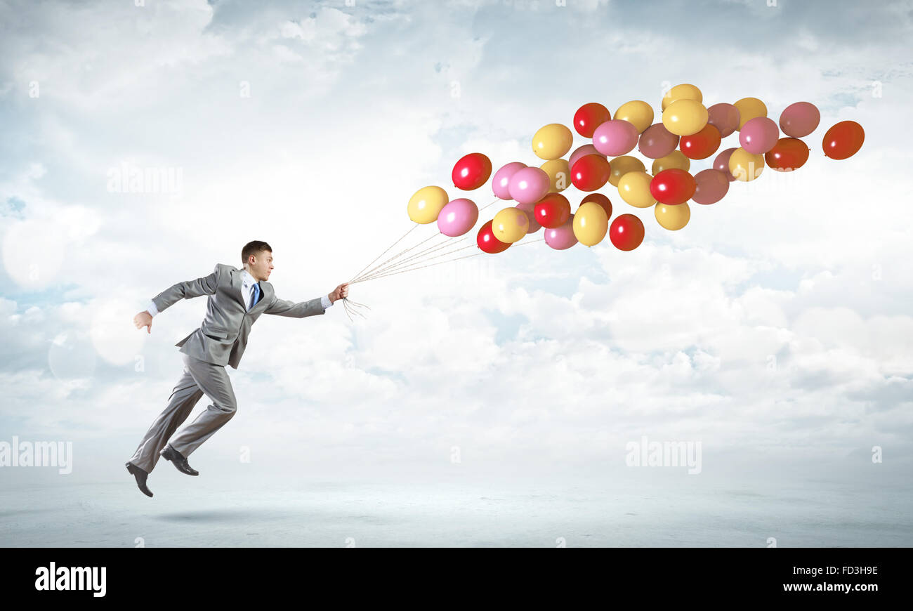 Cheerful businessman running with bunch of colorful balloons Stock ...