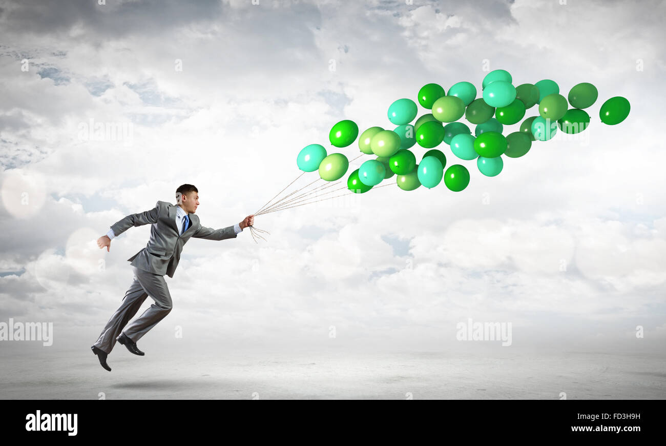 Cheerful businessman running with bunch of colorful balloons Stock ...