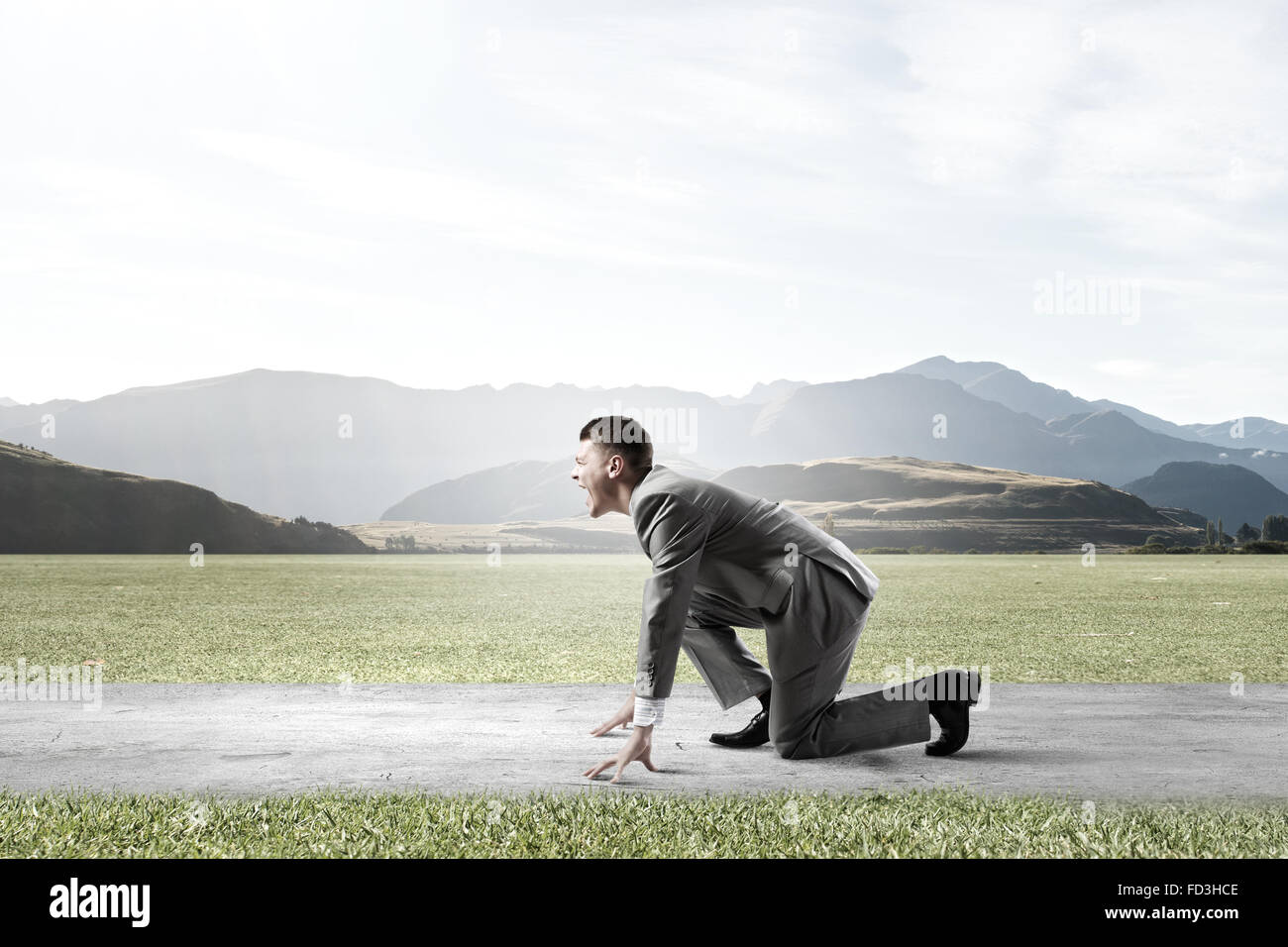 Side view of young businessman in start position ready to run Stock ...