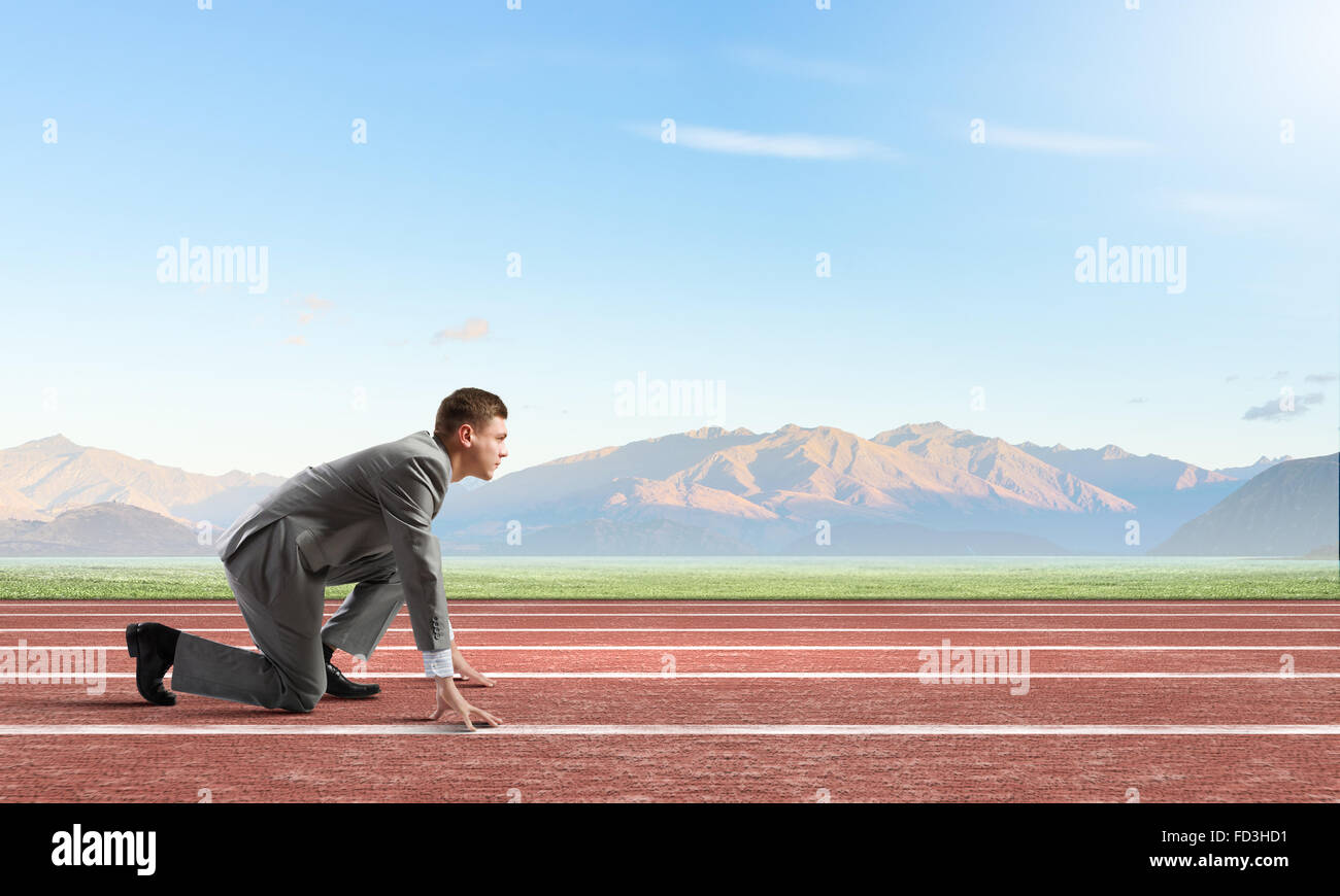 Side view of young businessman in start position on track Stock Photo ...