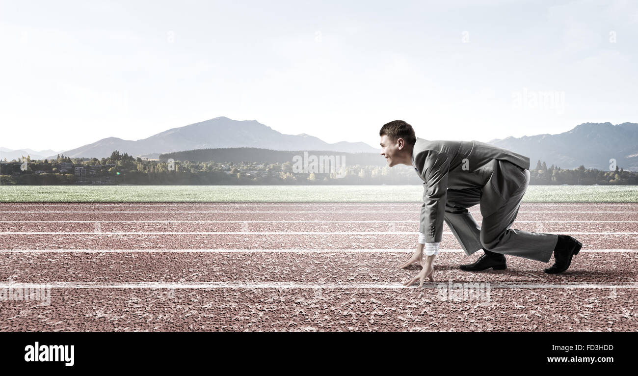 Side view of young businessman in start position on track Stock Photo ...