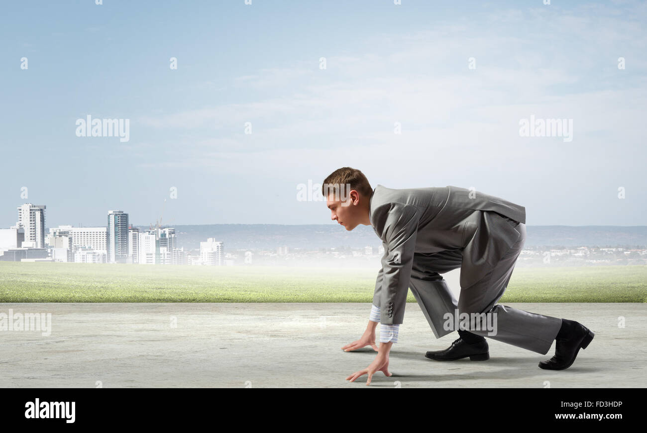 Side view of young businessman in start position ready to run Stock ...