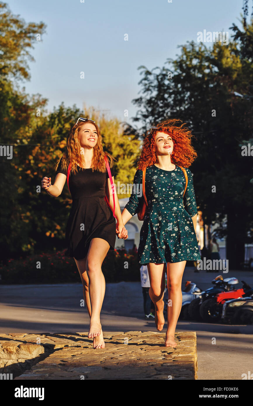 Best friends female students in a city park. Girl walking barefoot in ...