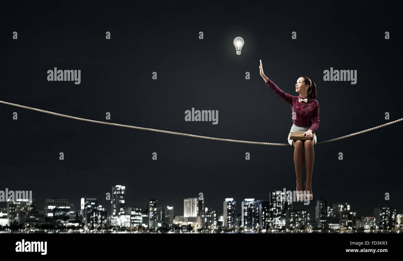 Young beautiful lady sitting on rope and reading book Stock Photo - Alamy