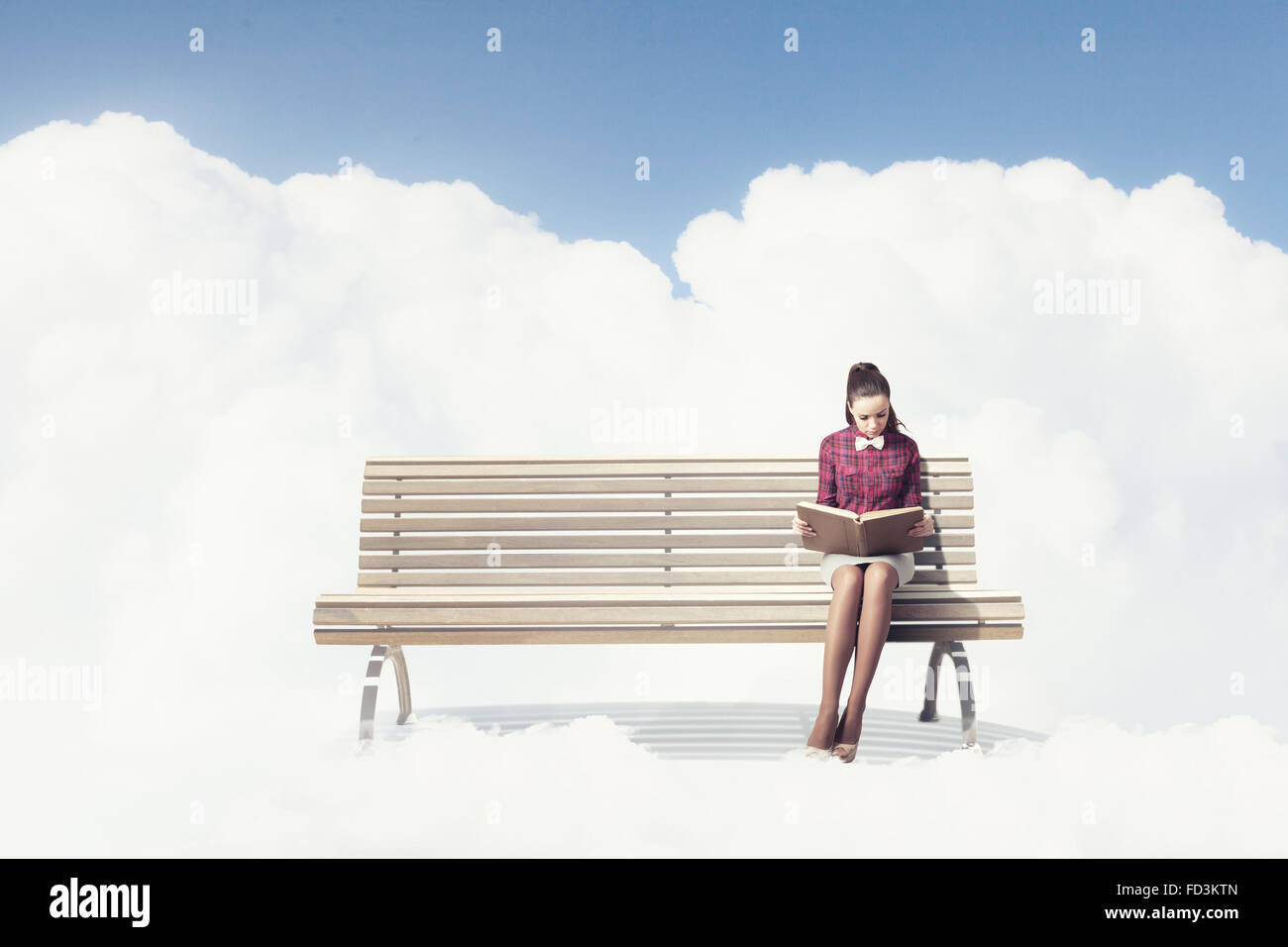 Young woman sitting on bench and reading book Stock Photo - Alamy