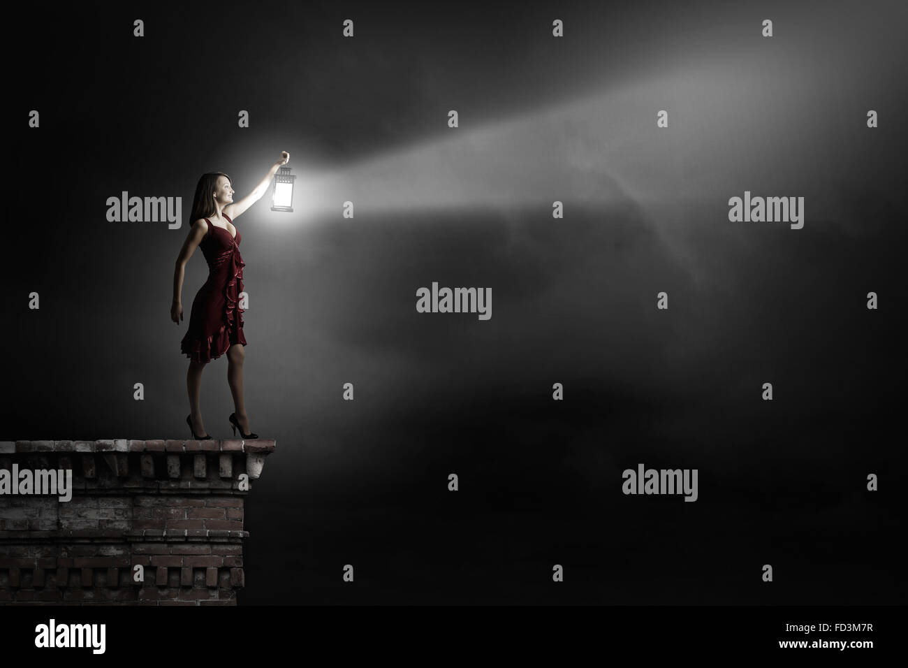 Young attractive woman in red dress with lantern walking in darkness ...