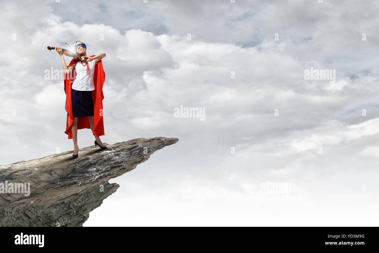Young woman in super hero costume playing violin Stock Photo - Alamy
