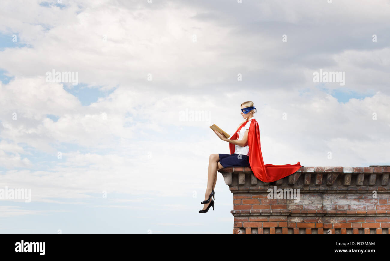 Young woman in super hero costume reading book Stock Photo - Alamy
