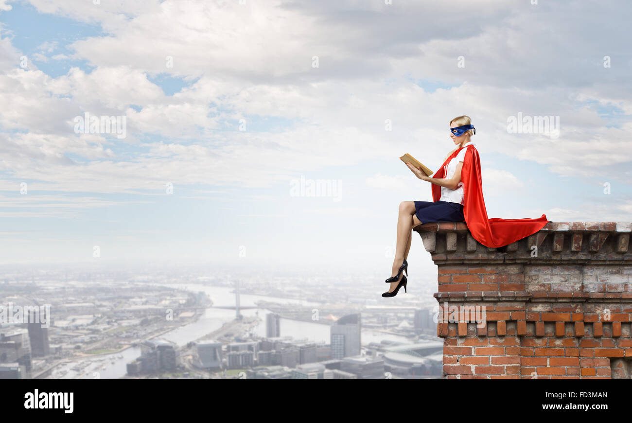 Young woman in super hero costume reading book Stock Photo - Alamy