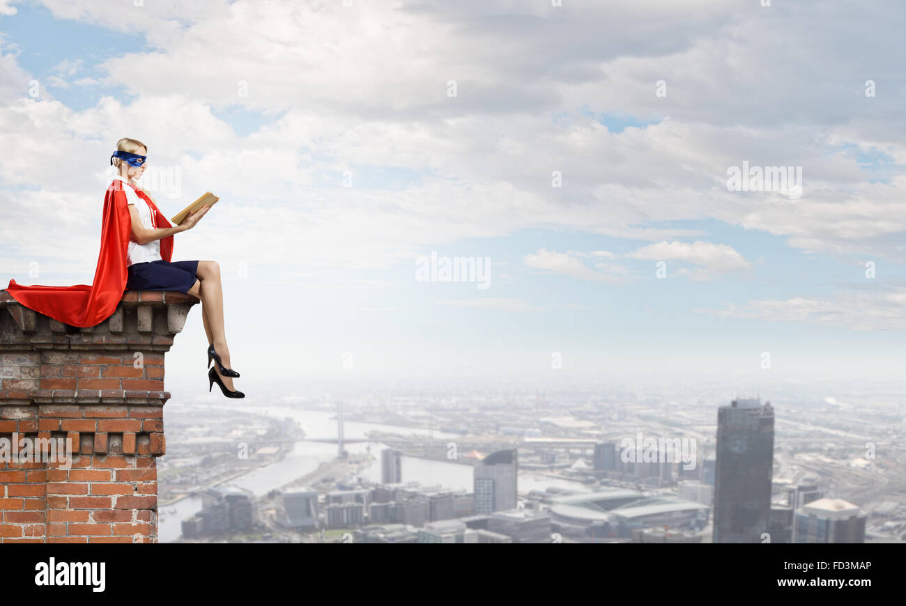 Young woman in super hero costume reading book Stock Photo - Alamy