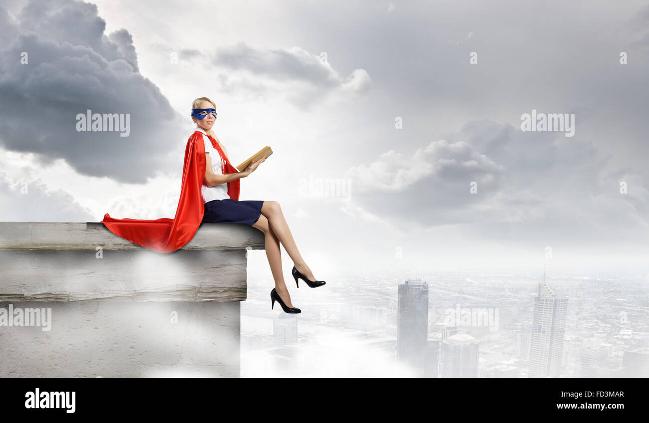 Young woman in super hero costume reading book Stock Photo - Alamy