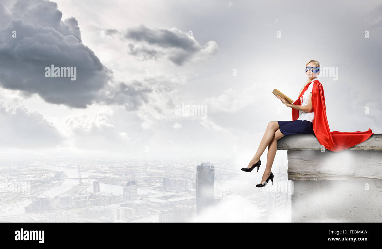 Young woman in super hero costume reading book Stock Photo - Alamy