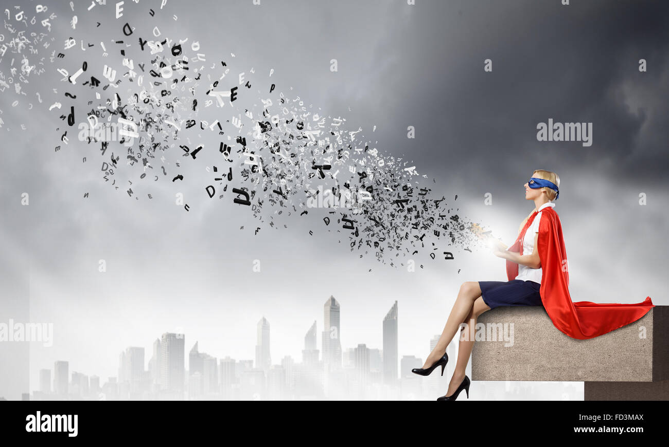 Young woman in super hero costume reading book Stock Photo - Alamy