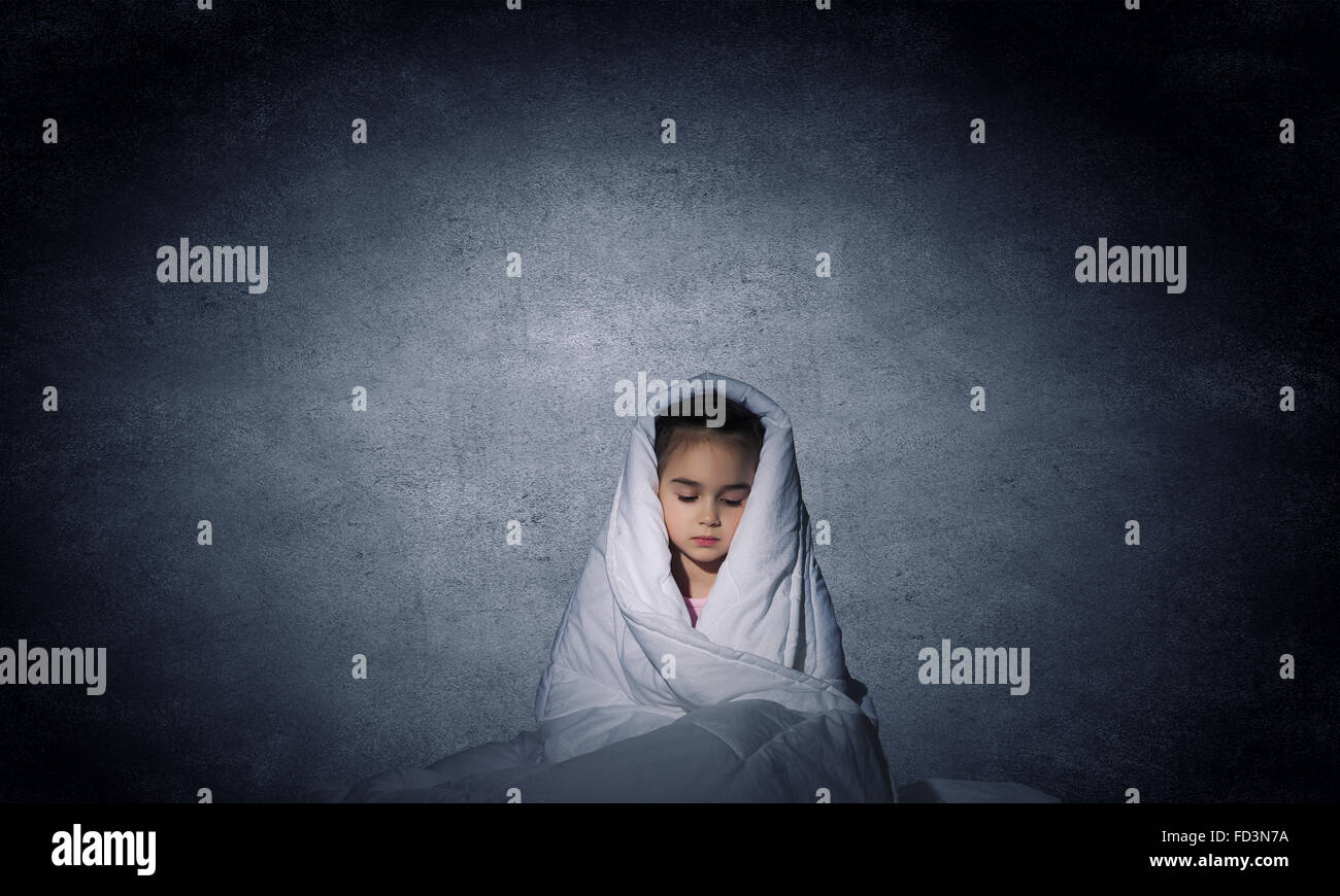 Cute scared girl sitting in bed under blanket Stock Photo - Alamy