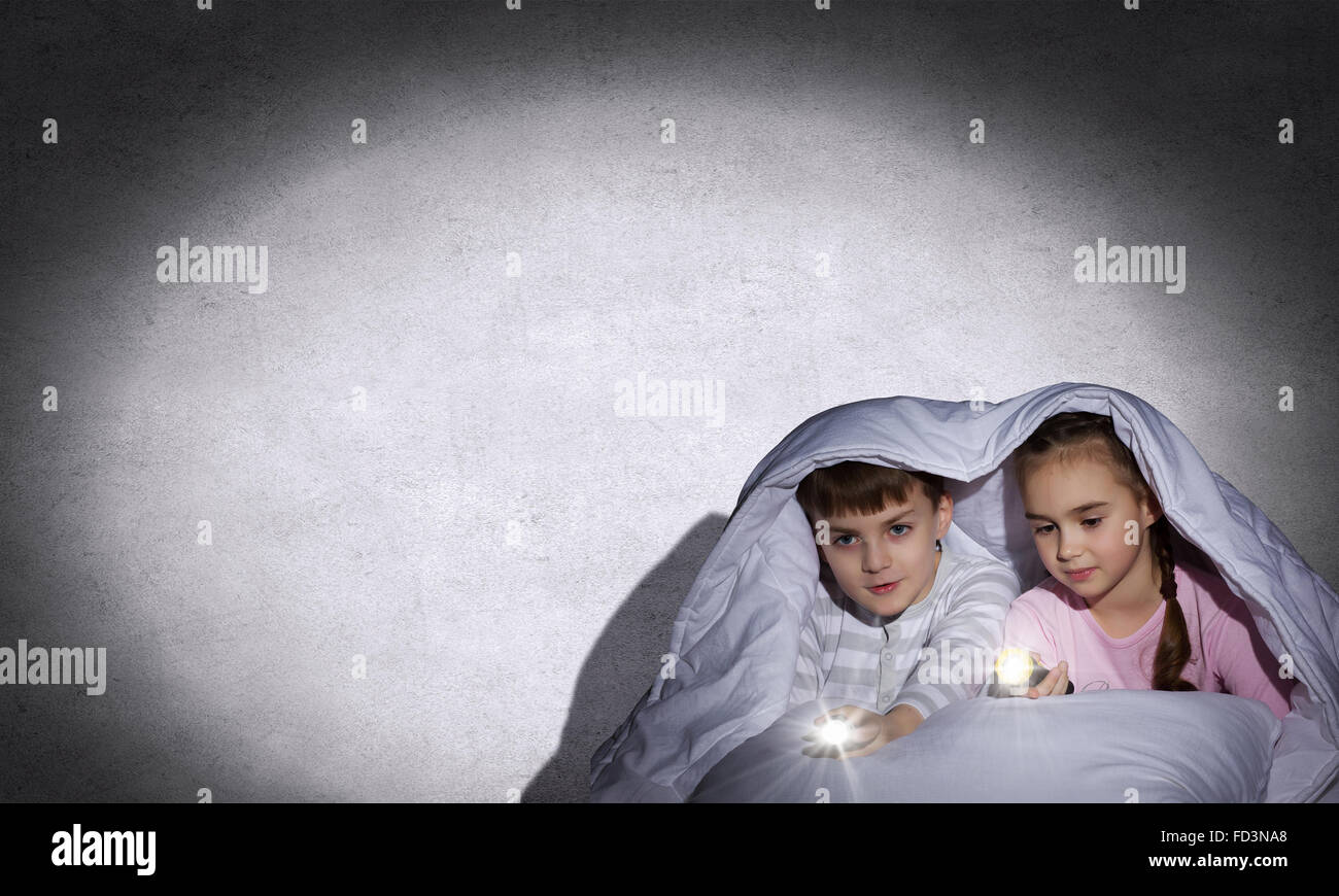 Children sitting in bed under blanket with flashlights Stock Photo - Alamy