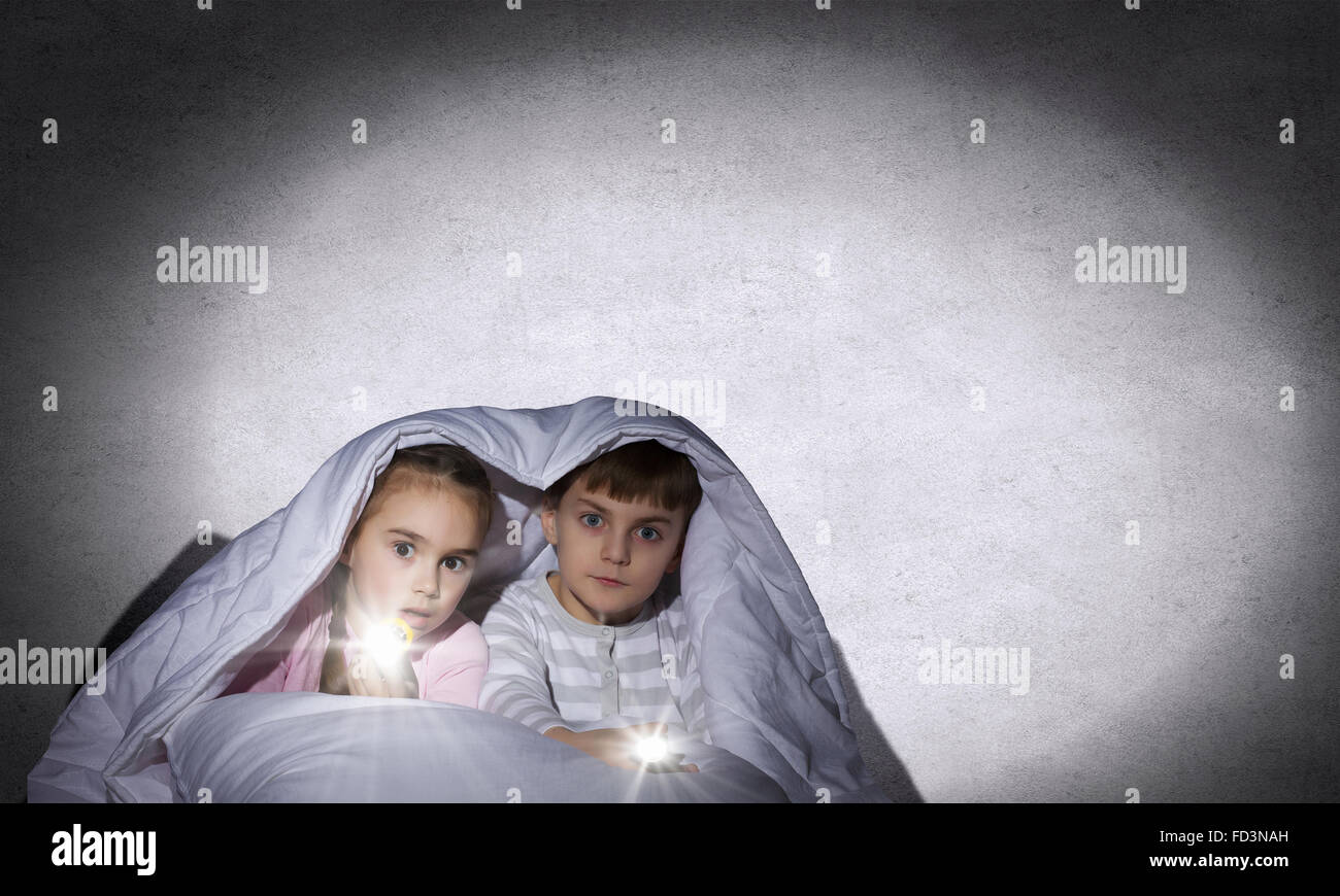 Children sitting in bed under blanket with flashlights Stock Photo - Alamy
