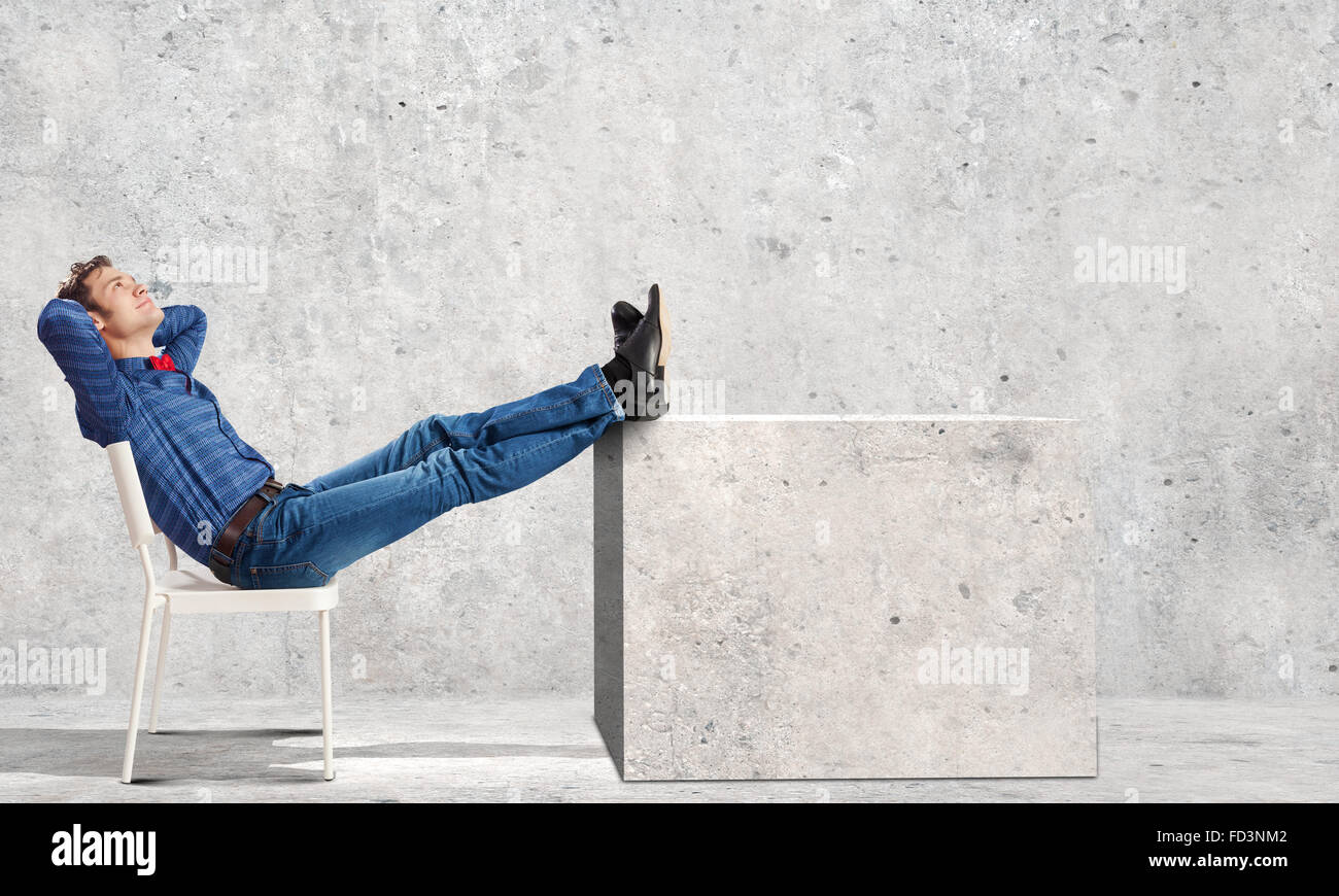 Young man sitting in chair with legs up and relaxing Stock Photo - Alamy