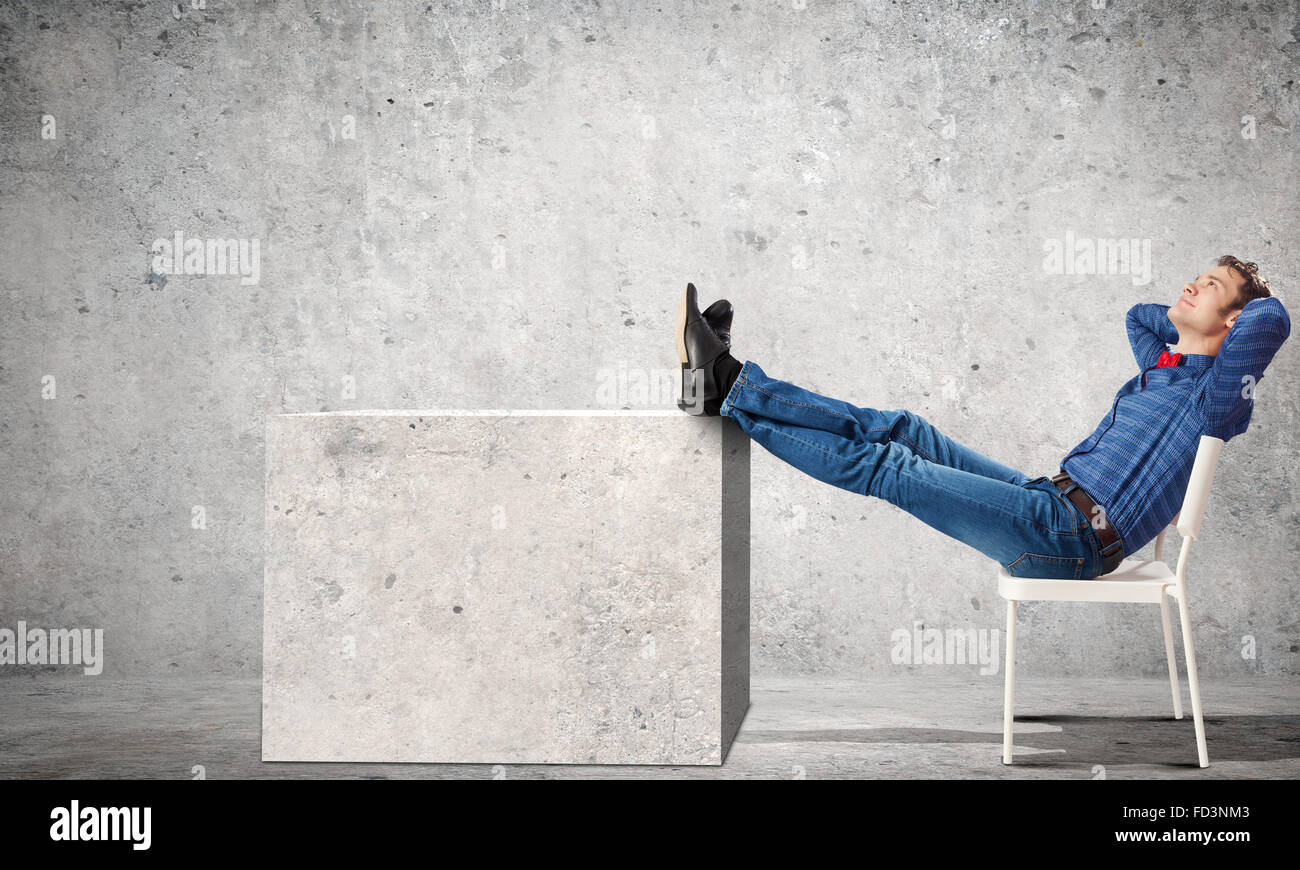 Young man sitting in chair with legs up and relaxing Stock Photo - Alamy
