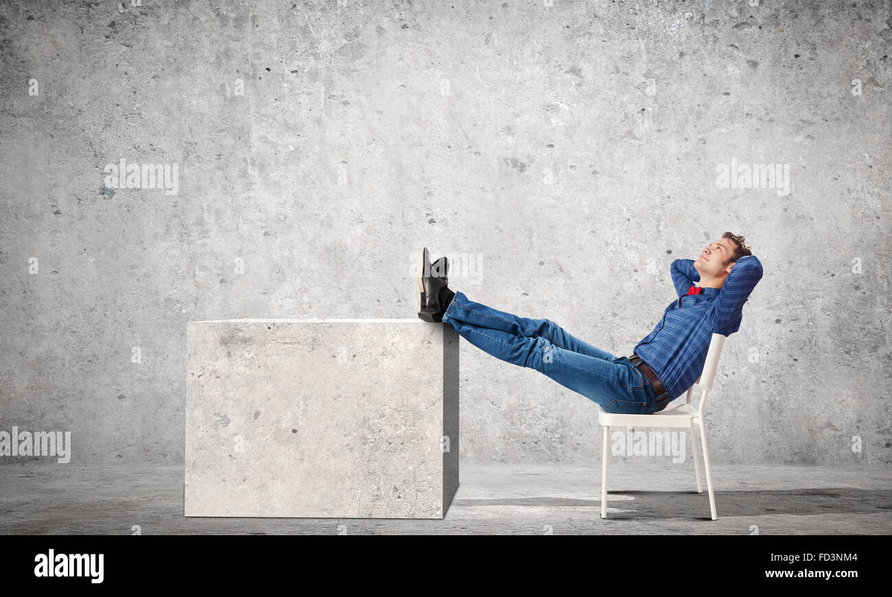 Young man sitting in chair with legs up and relaxing Stock Photo - Alamy